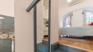 Um interior moderno com cozinha, escada e quarto.