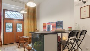 Uma cozinha compacta com área de refeições, uma geladeira pequena e uma janela com cortinas.