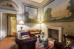 Uma sala de estar luxuosa com sofá de couro, mesa de centro de vidro e lareira.