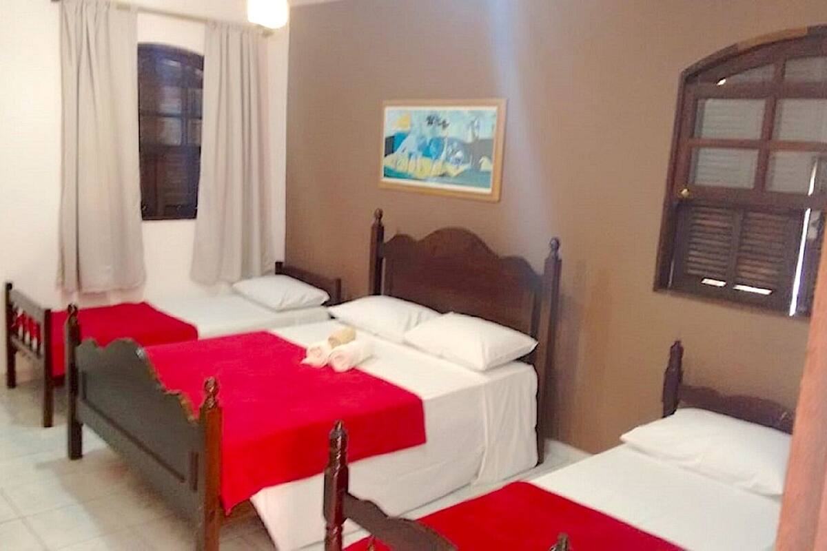 Um quarto com duas camas, um quadro na parede e uma janela com cortinas.