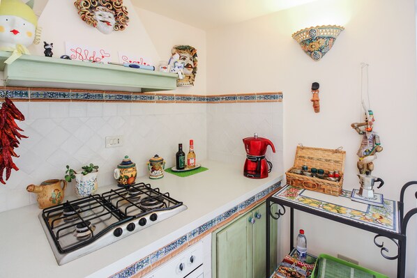 Uma cozinha com fogão a gás, cafeteira e diversos utensílios sobre o balcão.