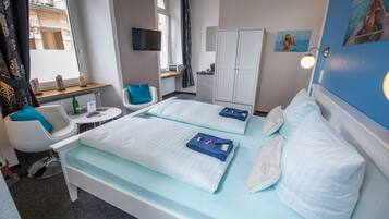 Quarto de hotel com duas camas, uma escrivaninha, uma cadeira, televisão e guarda-roupa.
