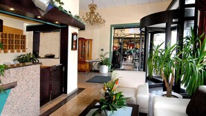 Um saguão de hotel com balcão de recepção, área de estar e vista para o restaurante.