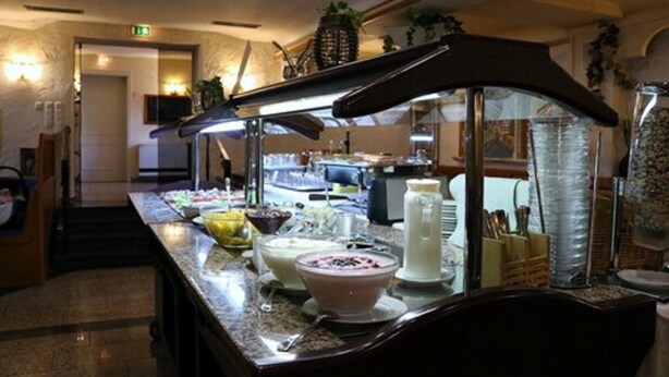 Disposição de buffet com diversos alimentos e um dispensador de bebidas.