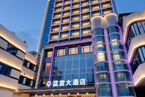 Um edifício moderno de hotel com uma placa de destaque, vários andares e um design arquitetônico singular.
