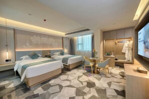 Quarto de hotel com duas camas, uma mesa, uma cadeira, televisão e um espelho grande.