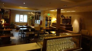 Um saguão de hotel com várias áreas de estar, uma recepção e uma vitrine com copos.