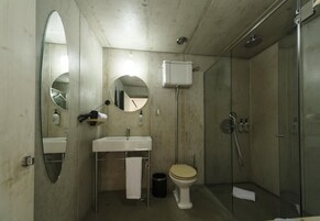 Casa de banho compacta com sanita, lavatório e chuveiro.