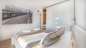 Quarto de hotel moderno com uma cama grande, um closet espaçoso e uma pintura de paisagem urbana na parede.