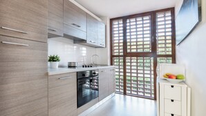 Cozinha moderna com armários de madeira, uma pia de aço inoxidável e um forno embutido.