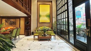Um hall com um sofá verde, uma mesa de centro, um lustre e uma grande janela com vista.