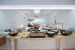 Disposição de buffet com diversos alimentos e um vaso de flores.