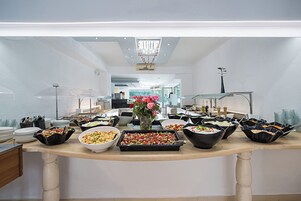 Disposição de buffet com diversos alimentos e um vaso de flores.