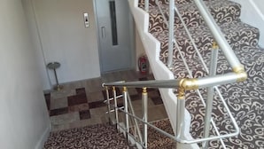 Uma escadaria com carpete estampado e corrimão de metal.
