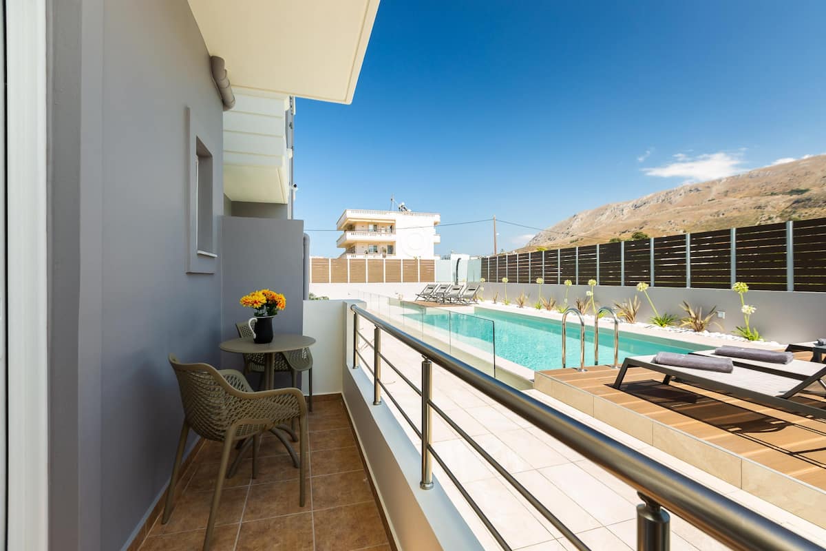 Uma varanda com piscina, espreguiçadeiras e uma mesa decorada com flores.