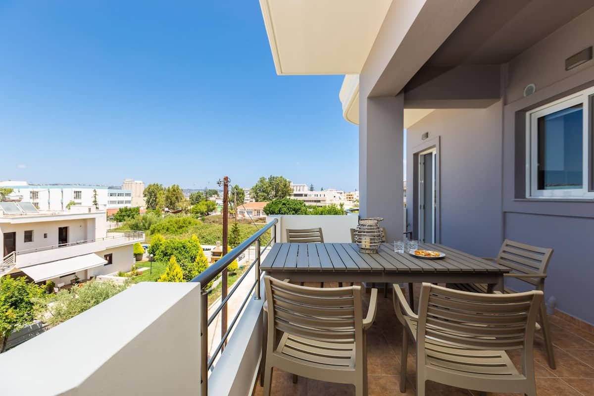 Uma varanda com mesa e cadeiras, com vista para uma área residencial.