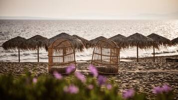 Uma praia com guarda-sóis de palha e gaiolas de pássaros de vime.