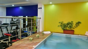 Uma academia com equipamentos de ginástica, um deck de madeira e uma piscina.