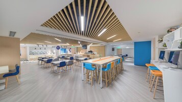 Um espaço de escritório moderno com uma mesa de reuniões central, estações de trabalho individuais e uma área de copa.