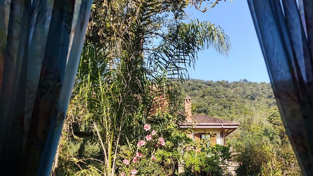 Uma casa com jardim, cerca de madeira e céu claro.