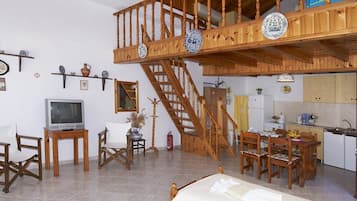 Uma sala de estar ampla com escada de madeira, televisão e mesa de jantar.