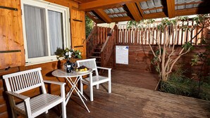 Um deck de madeira com uma mesa e duas cadeiras, uma escadaria e um cercado de madeira.