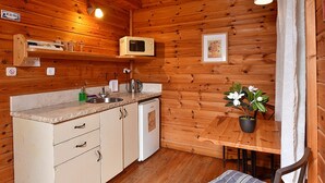 Uma cozinha rústica em estilo cabana, com micro-ondas, pia e geladeira.