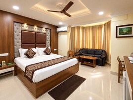 Quarto de hotel com cama grande, sofá, mesa de jantar e ventoinha no teto.