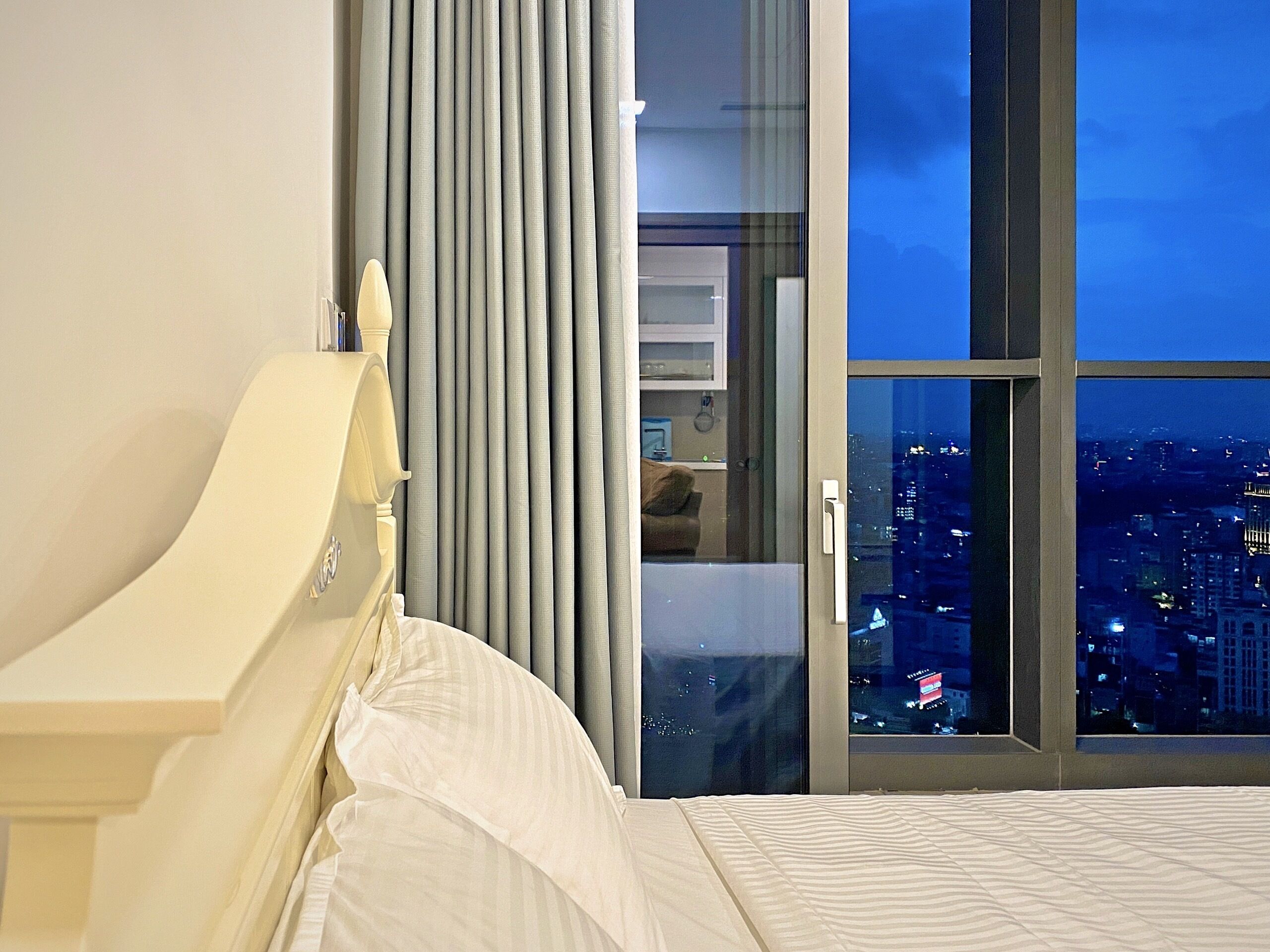 Quarto de hotel moderno com uma grande janela que oferece vista da cidade à noite.