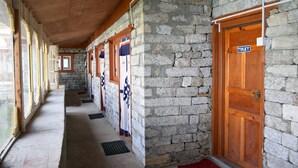 Corredor com paredes de pedra, portas de madeira e um sinal indicando um banheiro.