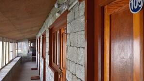 Um corredor com paredes de pedra e portas de madeira, cada uma marcada com um número.