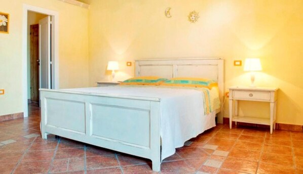 Um quarto com uma cama, duas mesas de cabeceira e um criado-mudo.