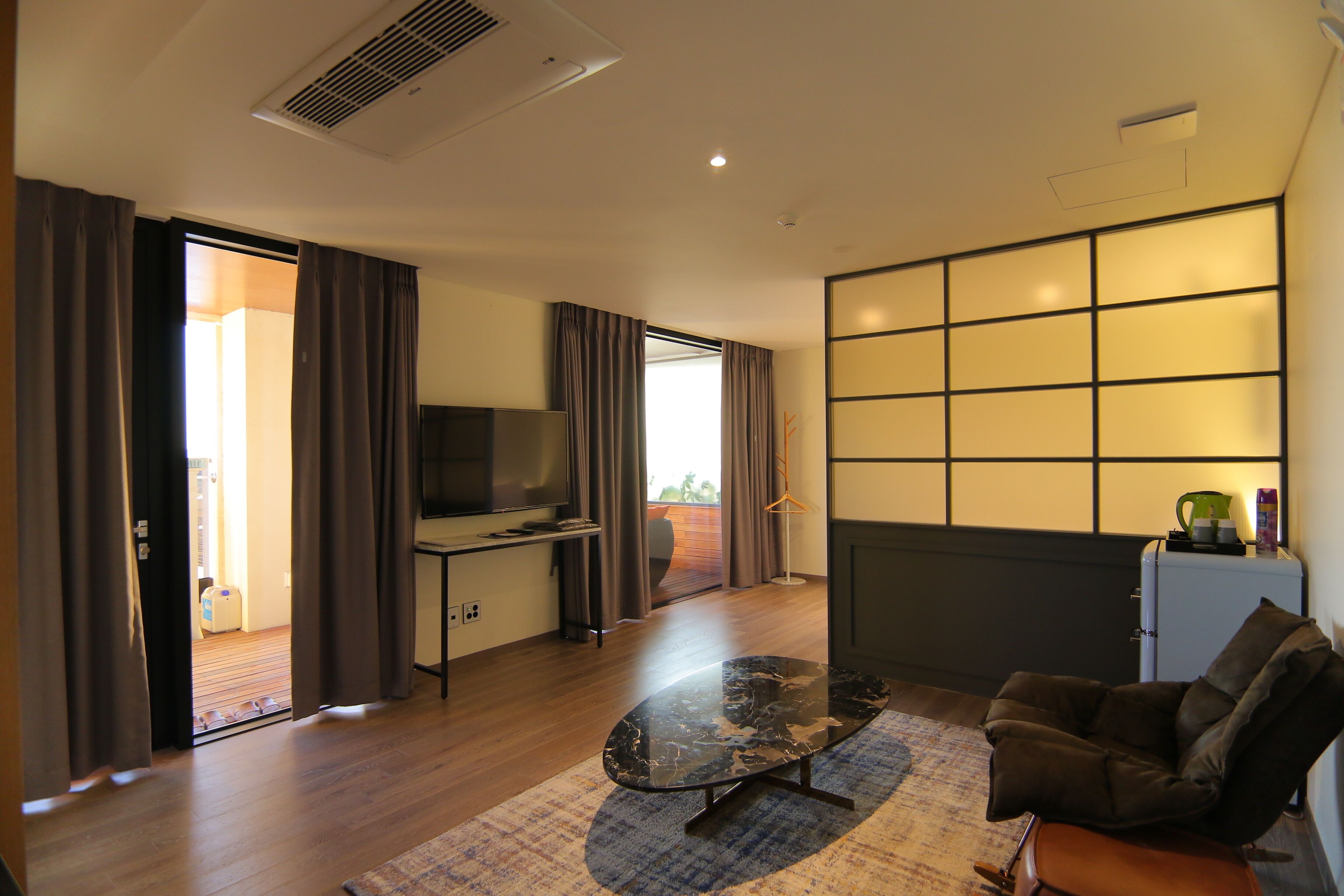 Uma sala de estar moderna com televisão de tela plana, sofá, mesa de centro e porta deslizante para uma varanda.