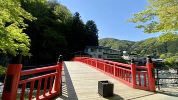 Uma ponte de madeira com grades vermelhas que leva a um edifício de fachada branca.