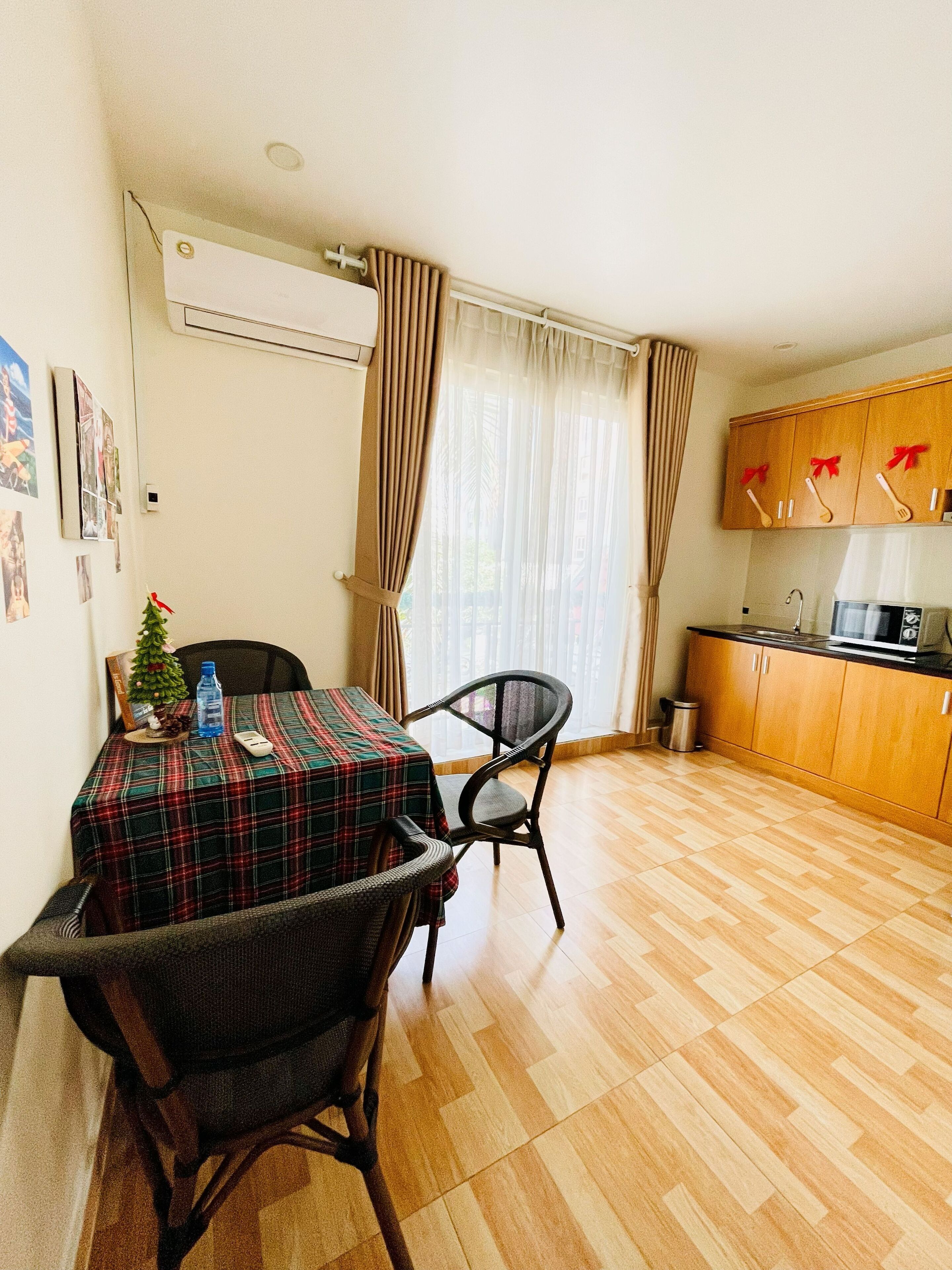 Um espaço compacto com área de refeições, cozinha compacta e uma pequena janela com cortinas.