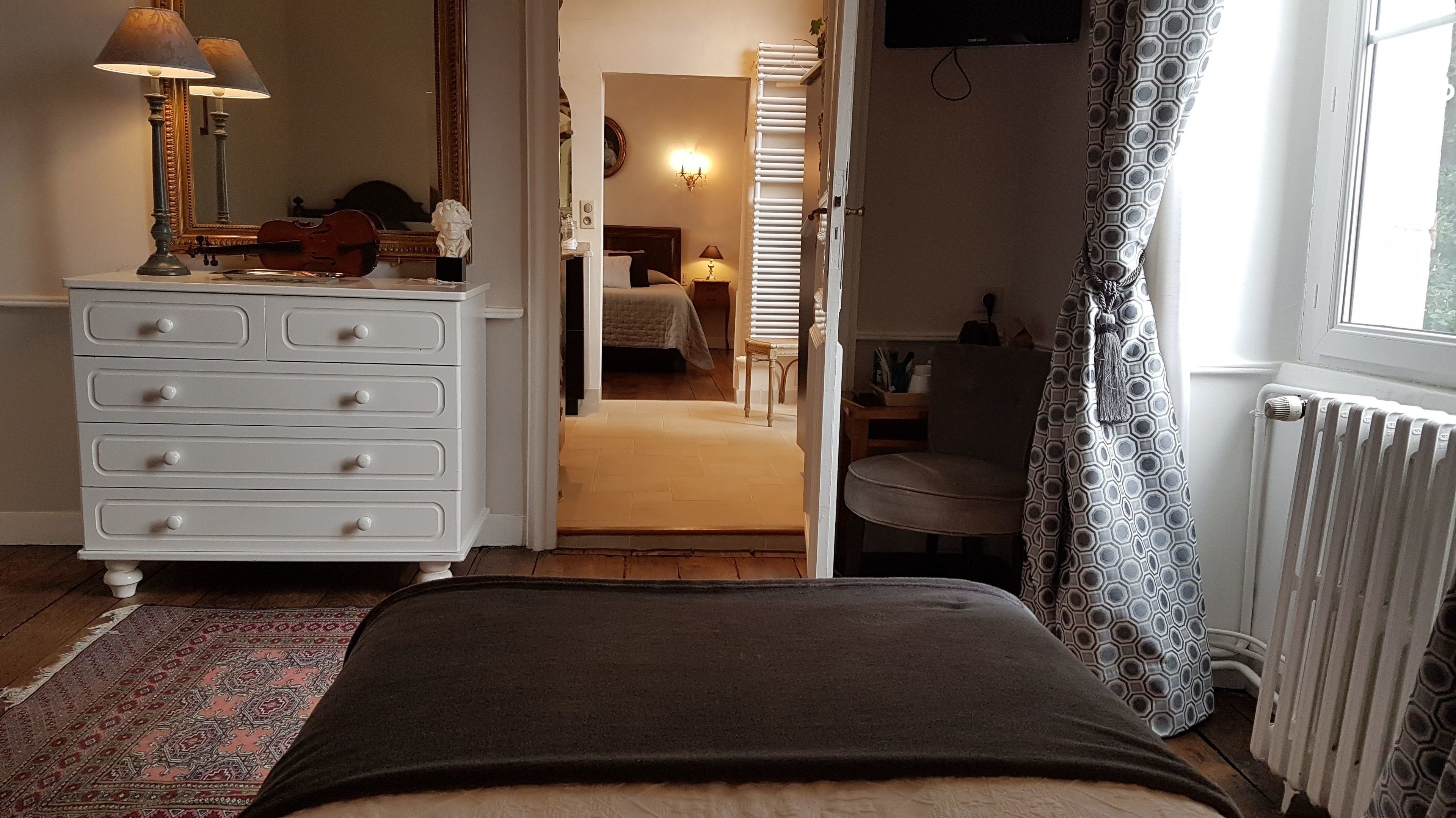 Quarto com cama, penteadeira, espelho e janela com cortinas.