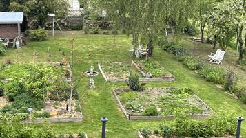 Um jardim bem cuidado com canteiros elevados, um bebedouro para pássaros e área de estar ao ar livre.