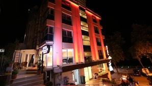 Um hotel moderno com entrada destacada, placa visível e fachada bem iluminada.
