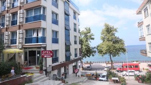 Um hotel com vista para o mar, área de estar ao ar livre e um ônibus vermelho ao fundo.