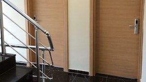 Uma escadaria que leva a um quarto com porta de madeira e puxador de metal.