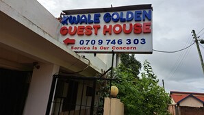 Placa para o Kwale Golden Guest House, com número de contato e seta indicativa.