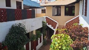 Um pátio com escadaria, um pequeno jardim e um edifício com telhado inclinado.