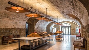 Um interior espaçoso com tetos abobadados, uma mesa comprida com garrafas de vinho e bancos.
