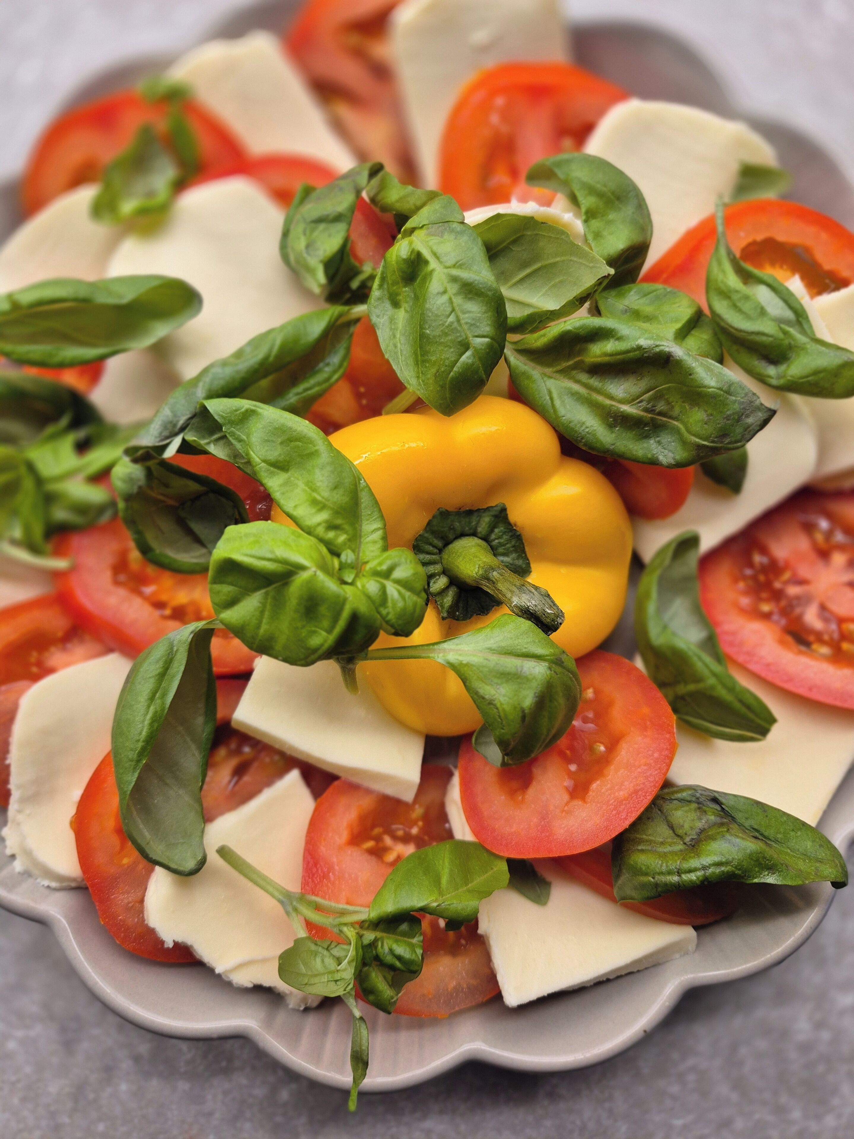 Uma salada Caprese com tomates, mussarela, manjericão e um pimentão amarelo.