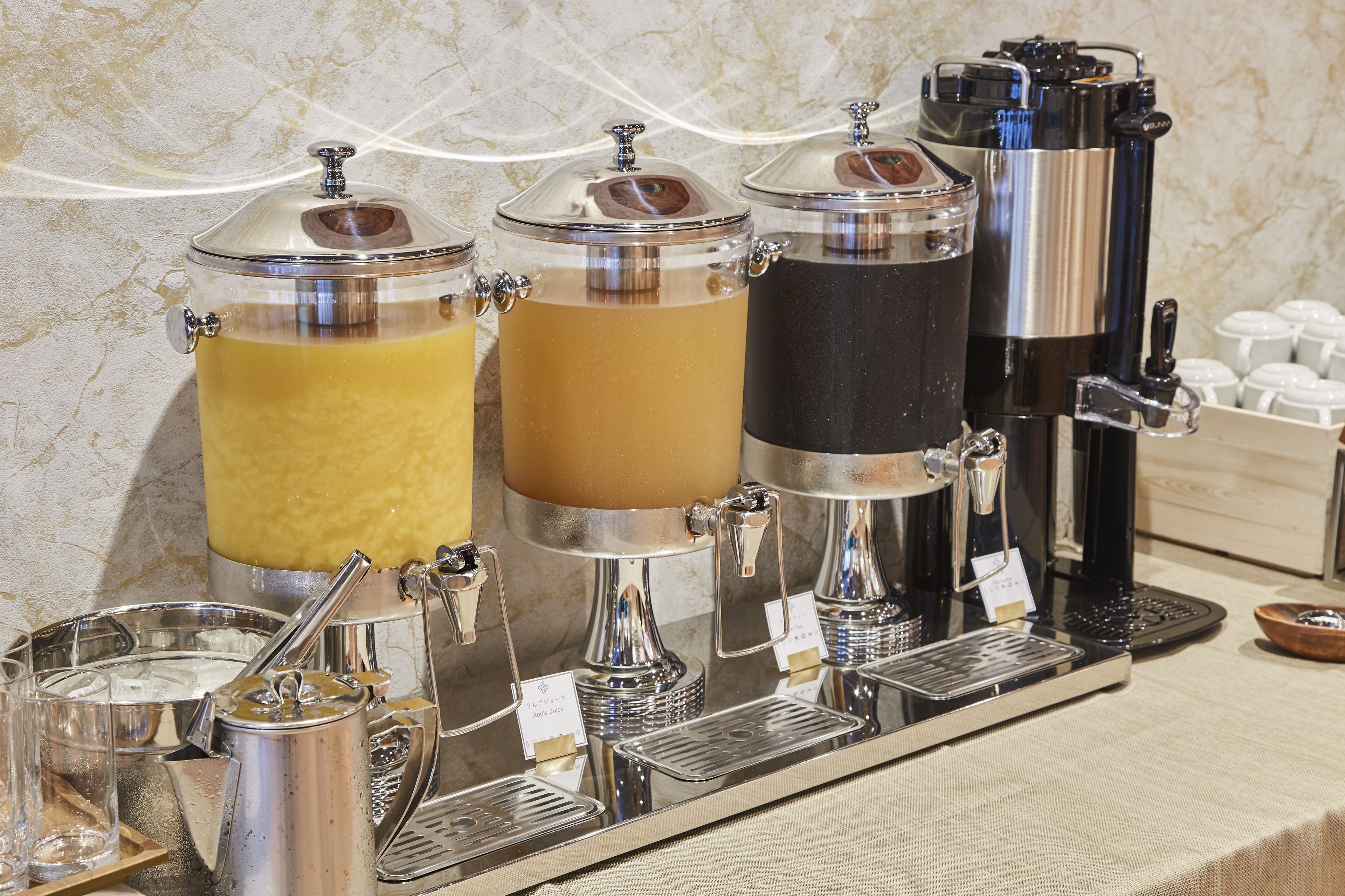 Uma área de bebidas com dosadores, copos e uma bandeja.