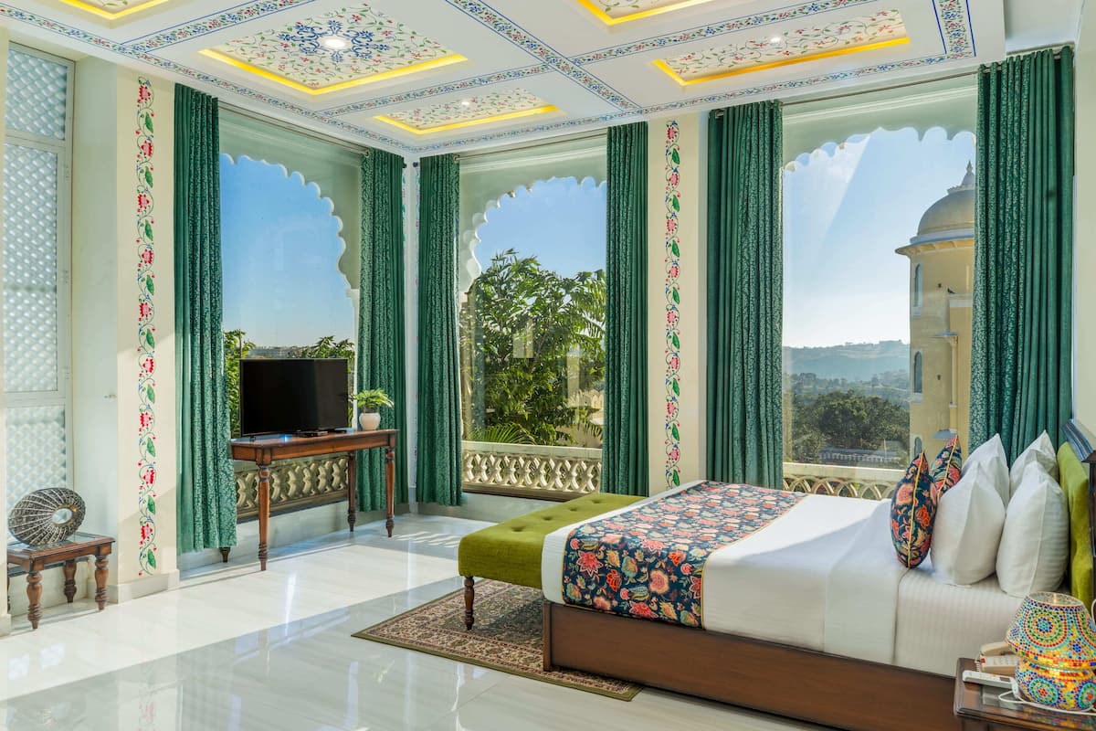 Quarto com cama grande, televisão e varanda com vista para um edifício.
