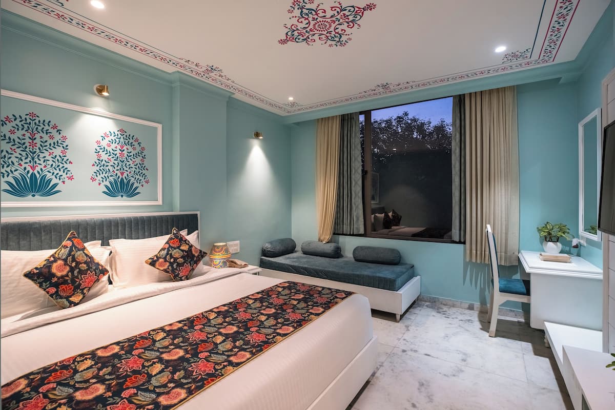 Quarto com cama, sofá, escrivaninha e janela.