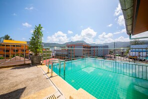Piscina no terraço com vista para edifícios e montanhas.
