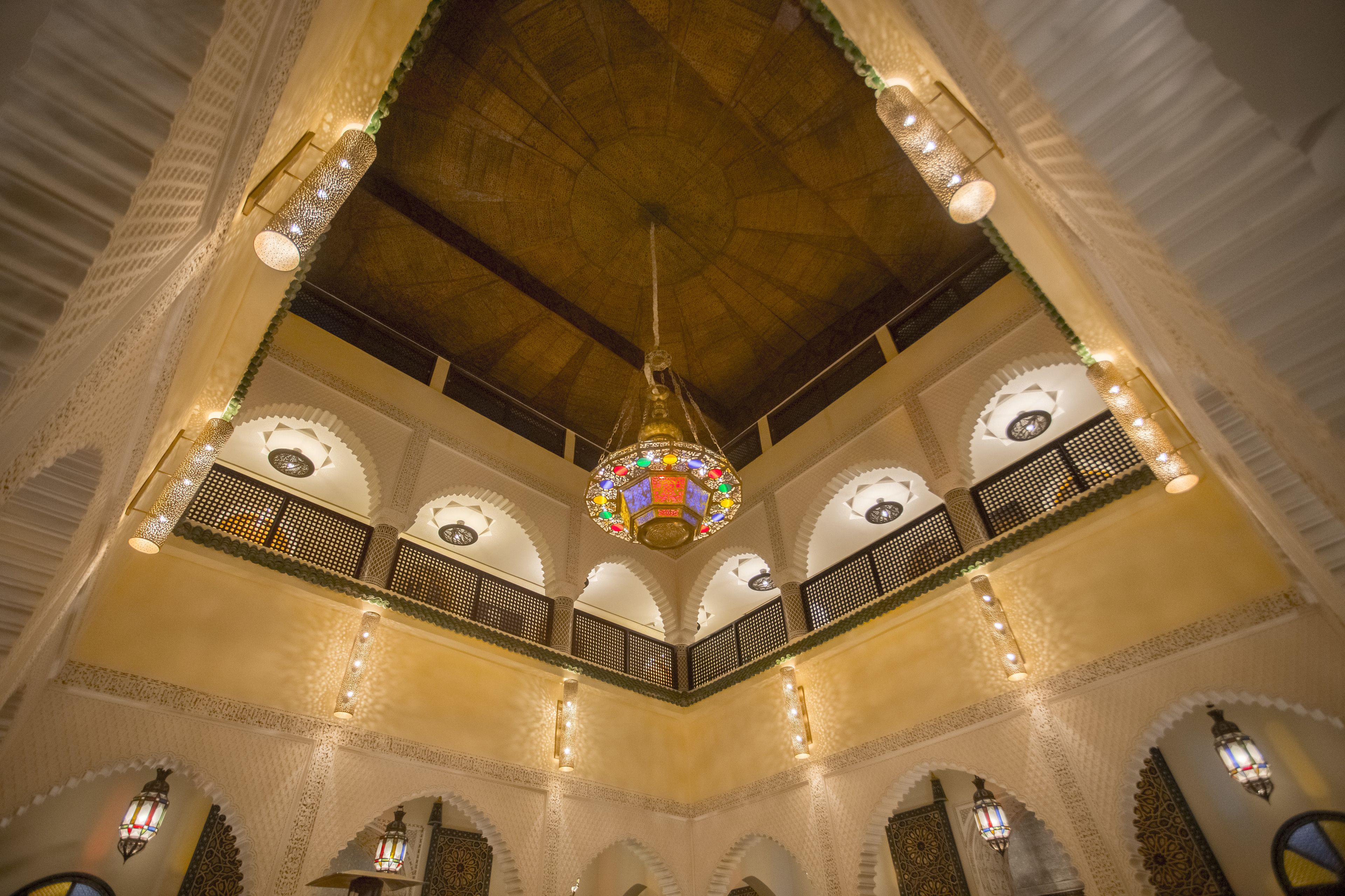 Interior com teto alto, arcos ornamentados e um lustre central.