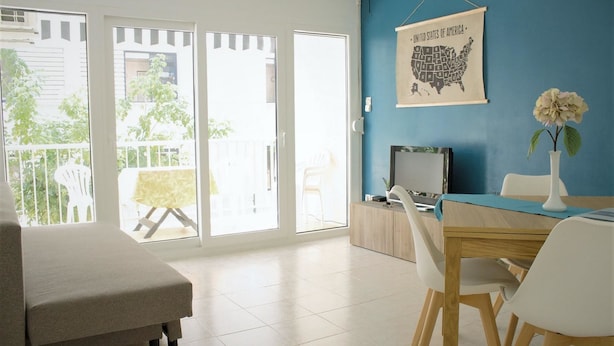 Um quarto claro com parede azul, um mapa dos EUA, uma mesa de jantar com cadeiras e um sofá.